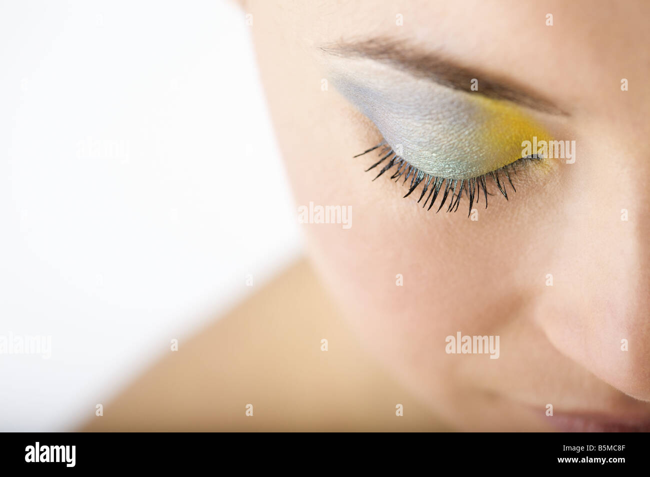 A woman wearing blue and yellow eyeshadow Stock Photo - Alamy
