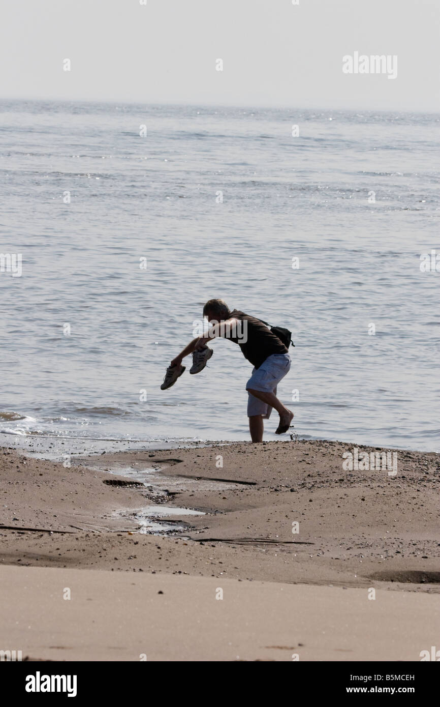 Man falling over with feet trapped in the sand on the beach with shoes ...