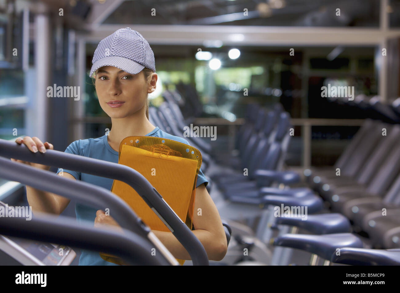 A woman standing by exercise equipment holding a clipboard Stock Photo ...