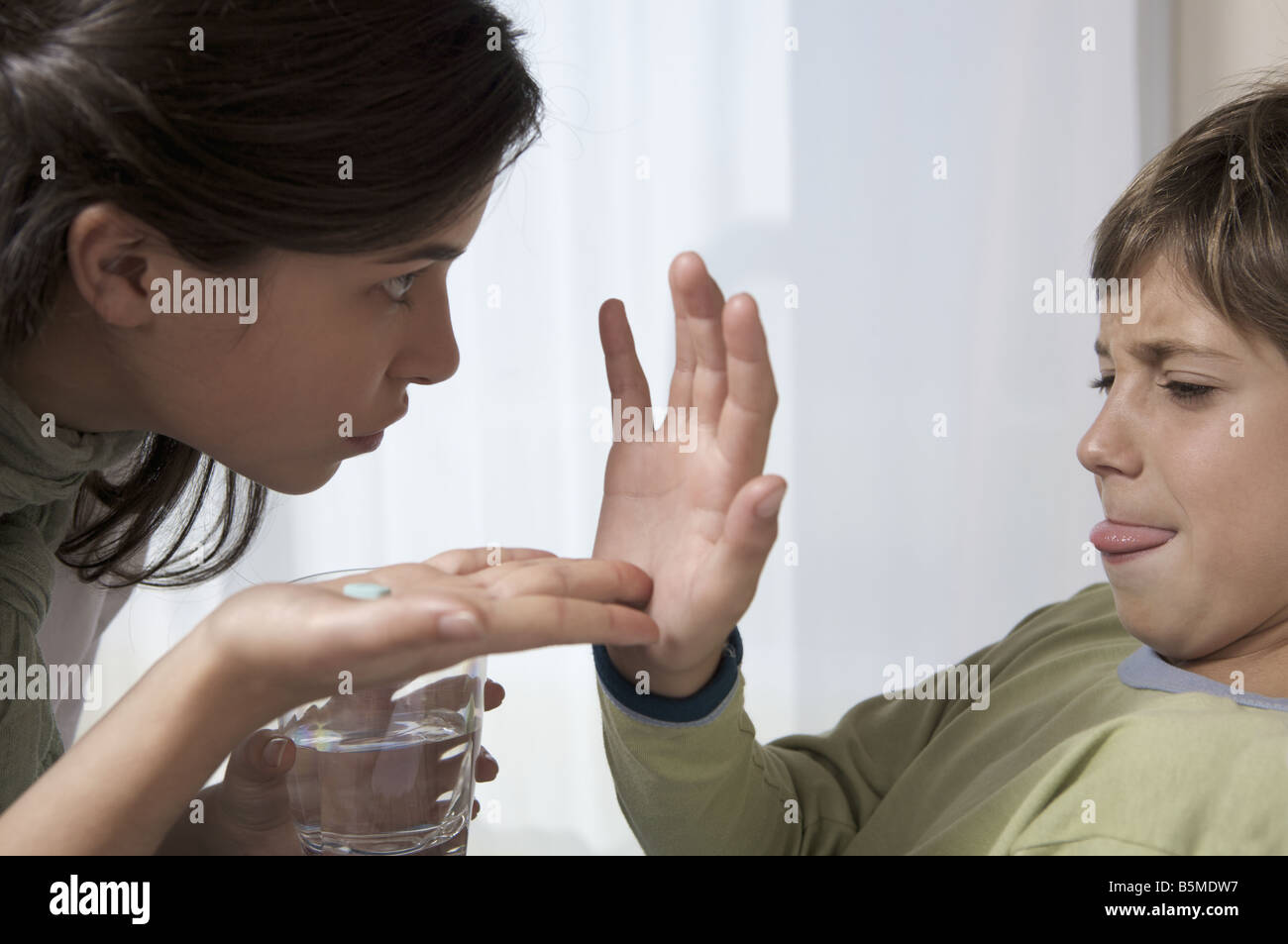 A boy in bed rejecting pills from a woman Stock Photo - Alamy