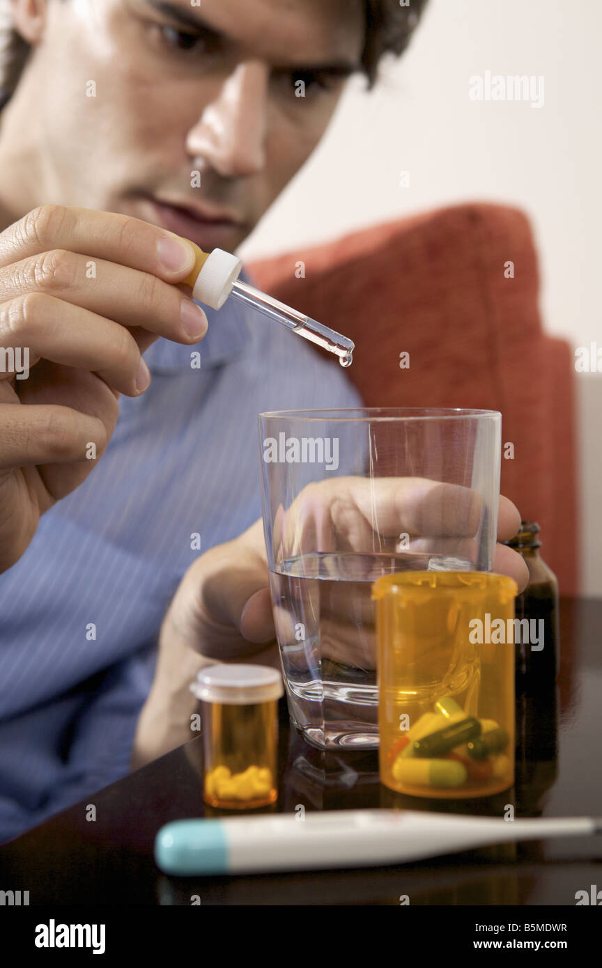 A man putting drops into a glass Stock Photo - Alamy