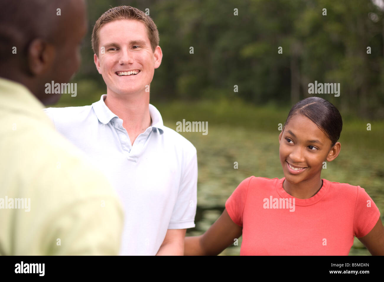 Three young people, two men and one woman, hang out at a dock in ...