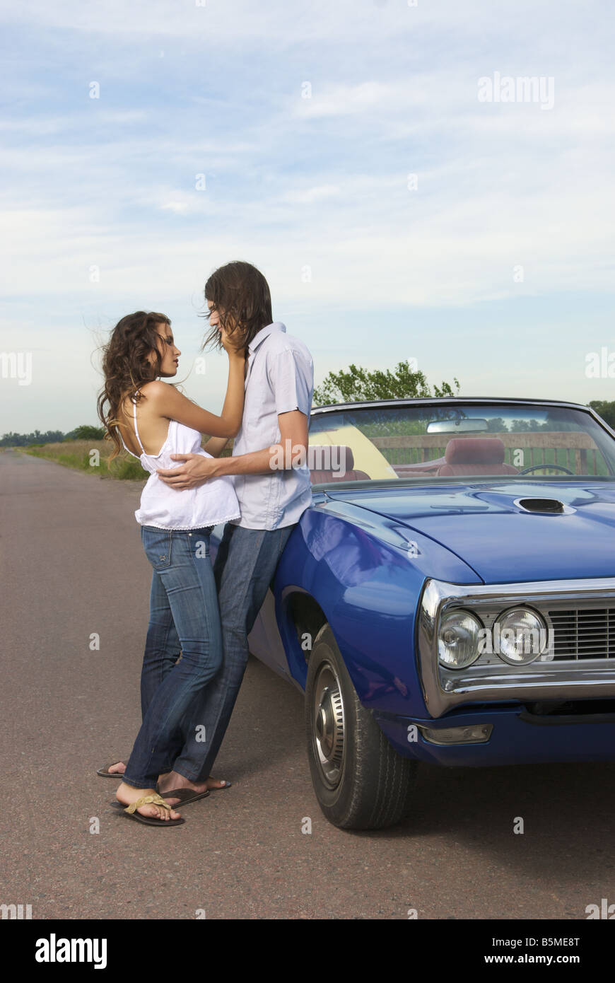 A couple leaning against a car Stock Photo - Alamy