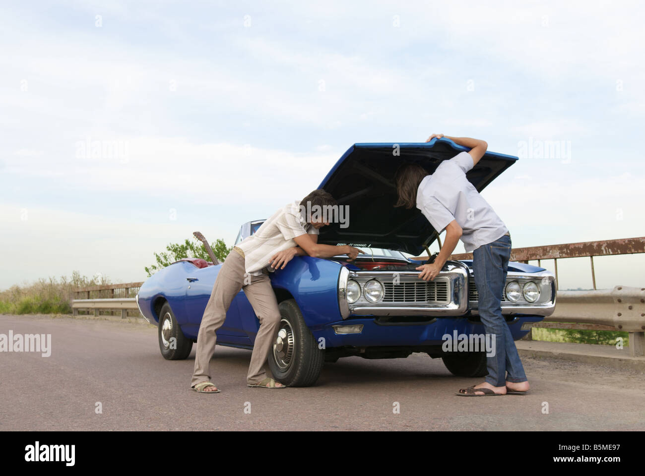 Two males looking under the hood of a car Stock Photo - Alamy