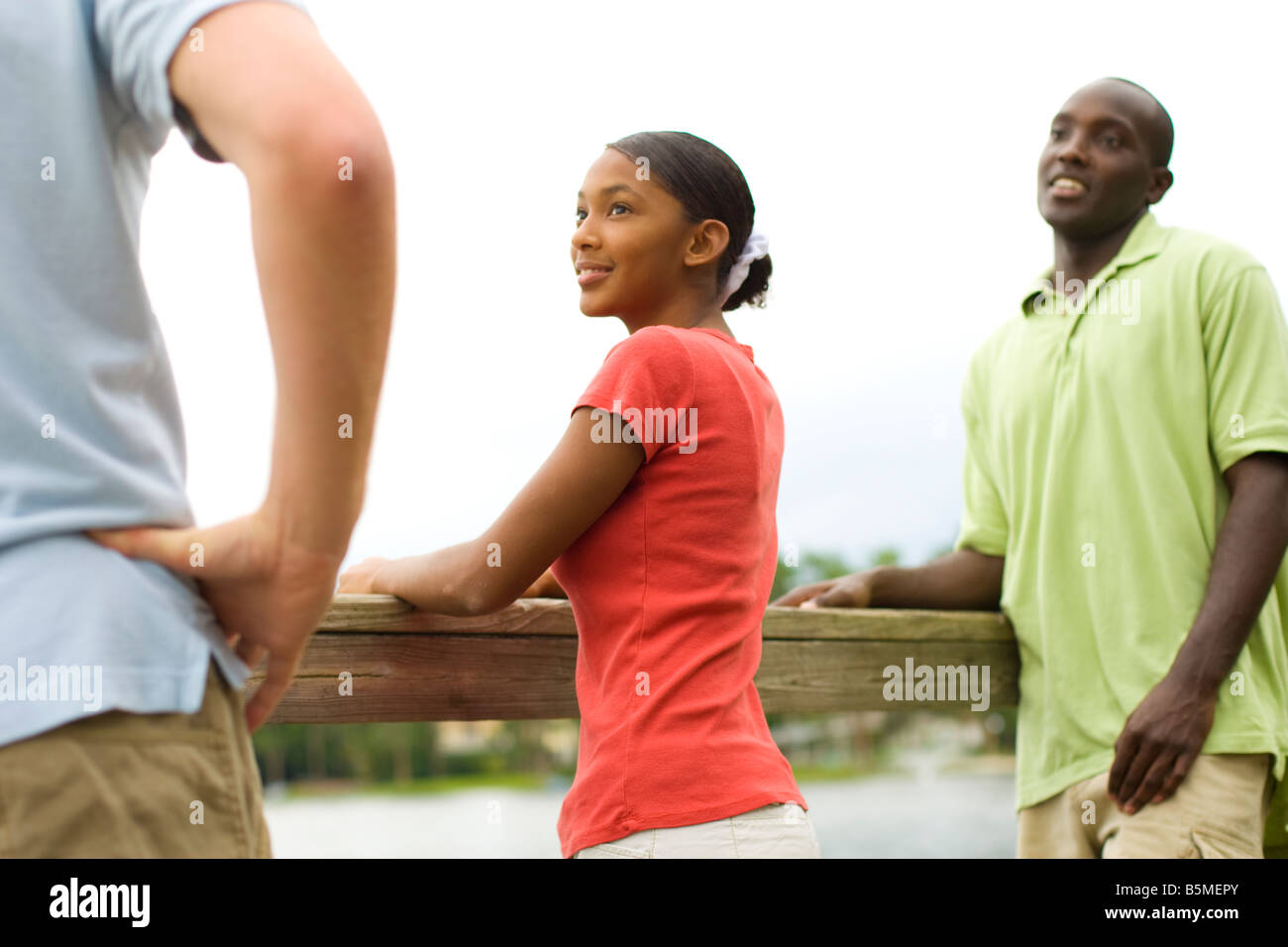 Three young people, two men and one woman, hang out at a dock in ...