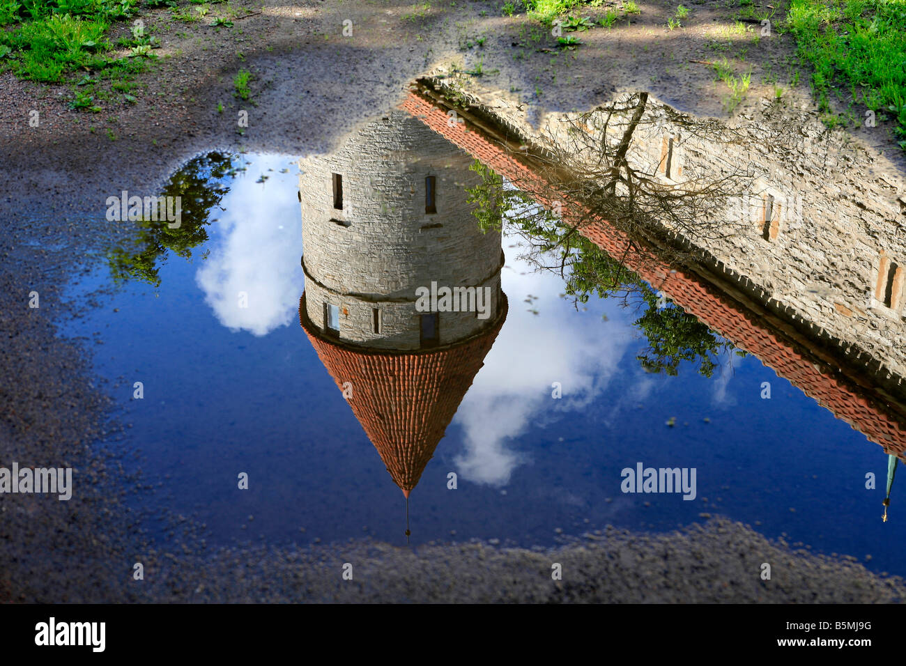 Reflection in a pool of water of medieval castle tower and rampart in ...