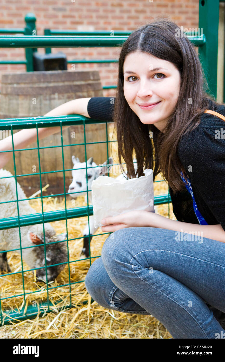 A young woman feeding a baby lamb and a baby goat at a farm Stock Photo ...