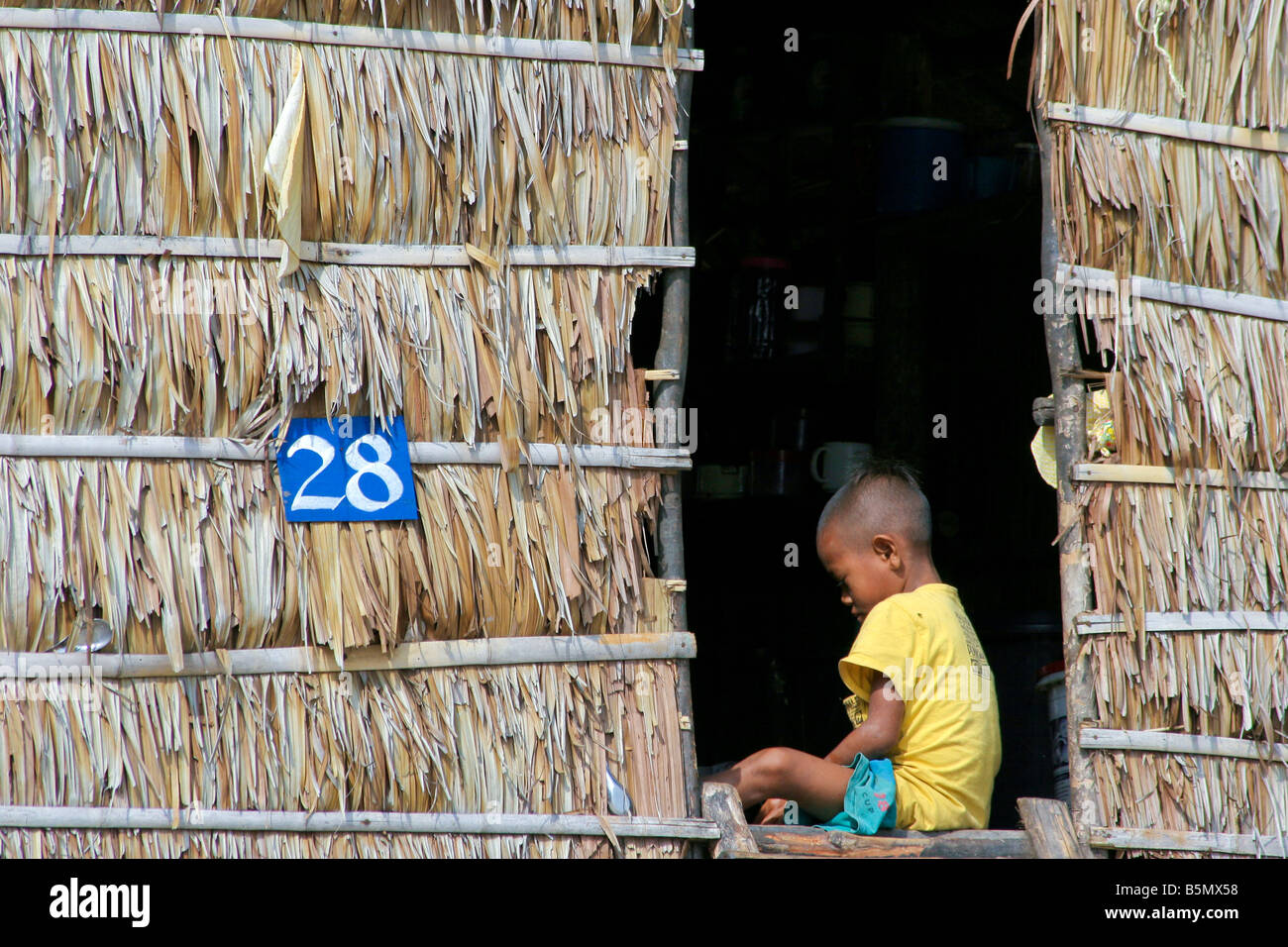 moken boy (sea gypsy) seated in traditional straw hut, mu ko surin ...