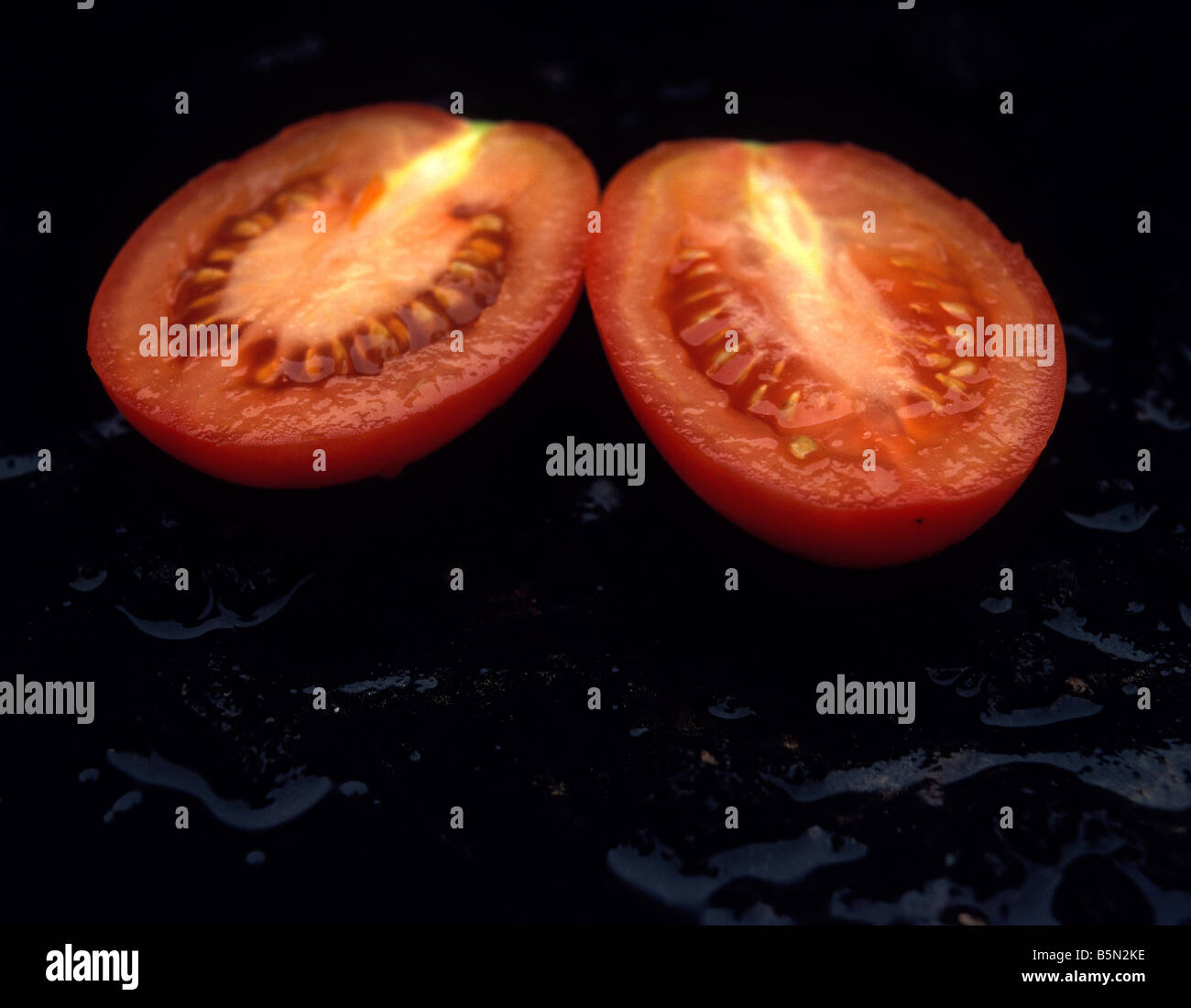 A tomato cut in half on a bed of soil Stock Photo - Alamy