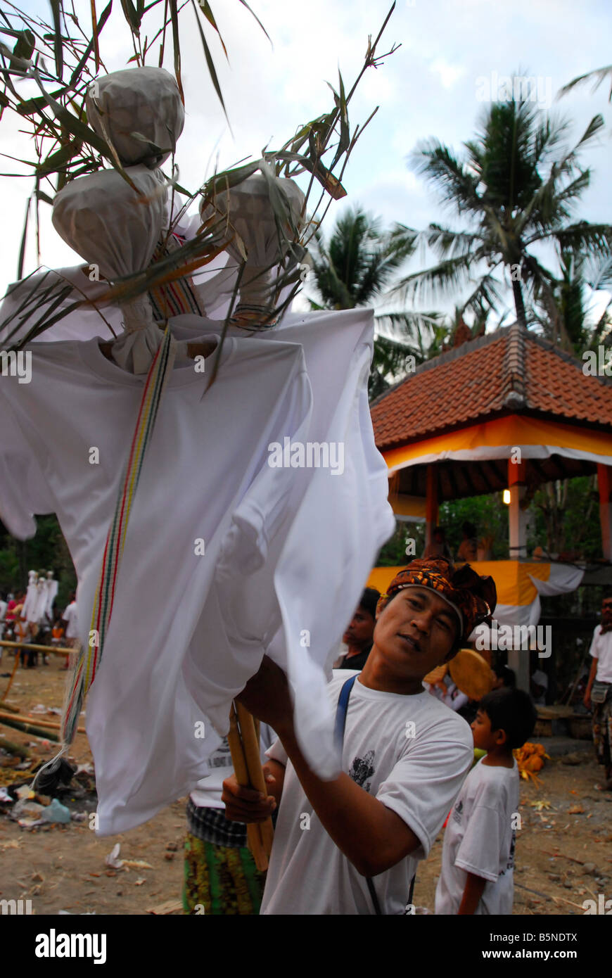 Balinese man hold the efigies of the dead to be thrown into the fire ...