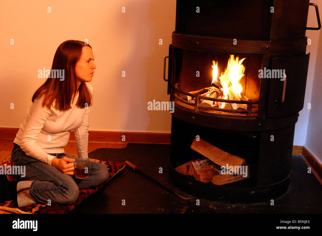 Girl sitting by the fire Stock Photo - Alamy