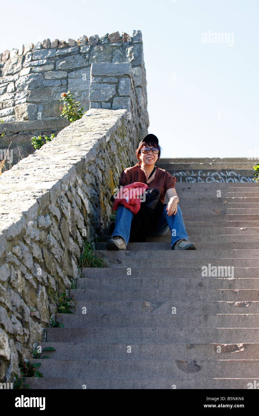 Chinese woman sitting on steps and smiling Stock Photo - Alamy