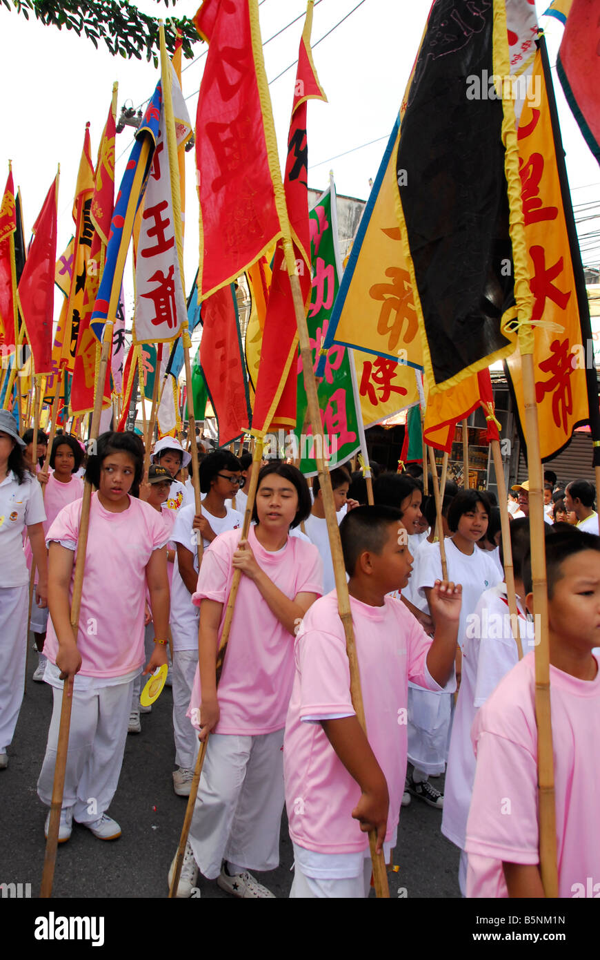 School kids holding flag during street procession at Phuket vegetarain ...