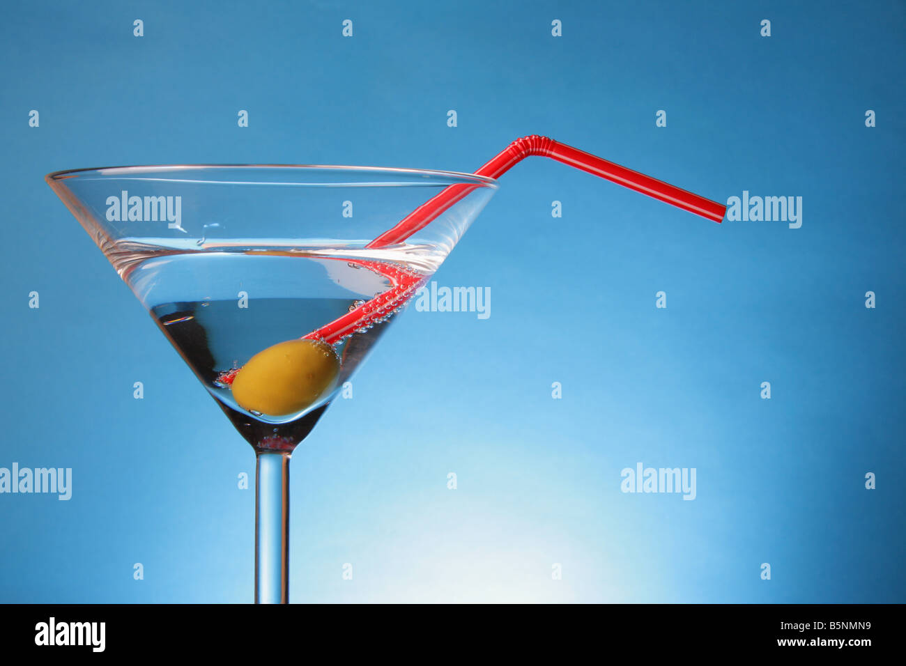 Martini glass with olive and red straw over blue background Stock Photo ...