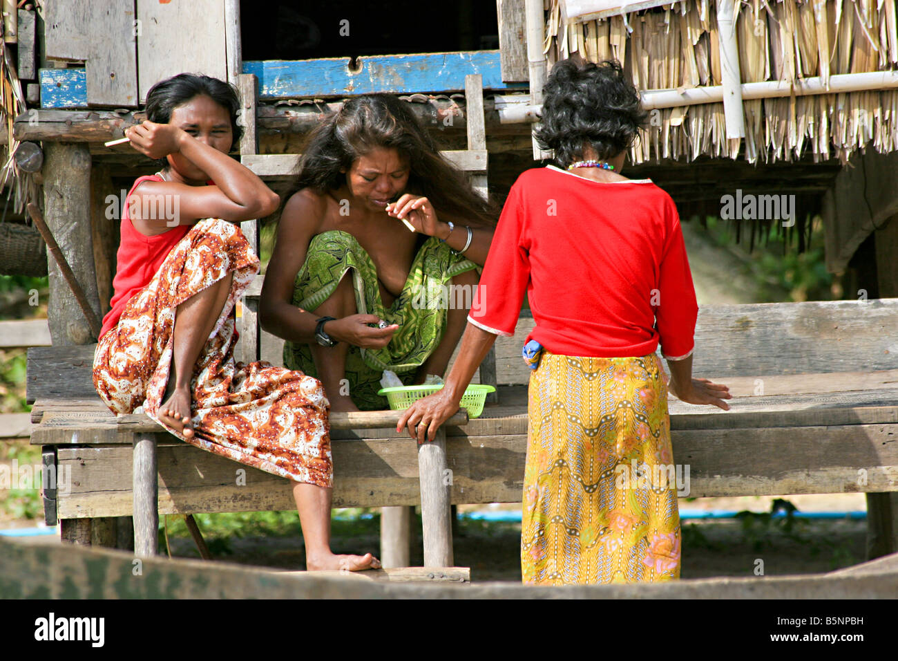seated moken women (sea gypsy) talking and smoking, mu ko surin ...