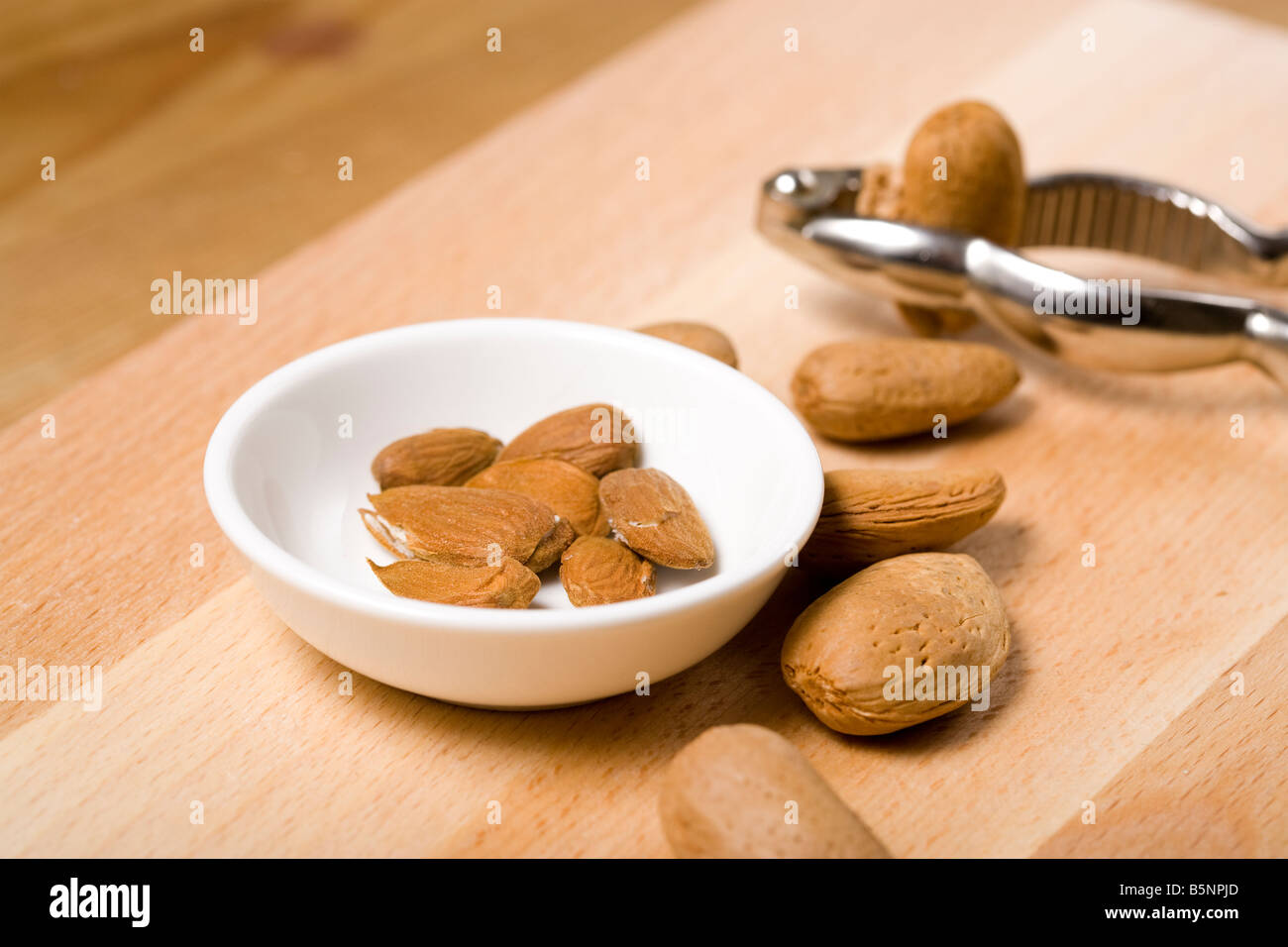nutcracker, almonds and cracked almonds in white bowl Stock Photo - Alamy