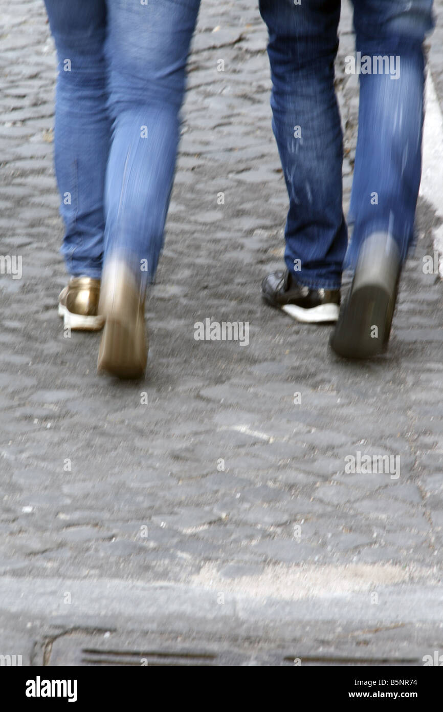 two people wearing jeans walking on street in town Stock Photo - Alamy