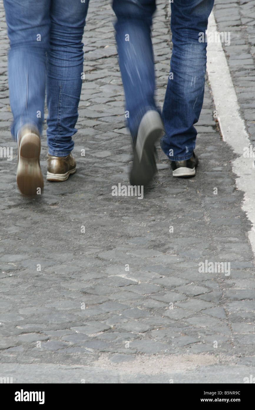 two people wearing jeans walking on street in town Stock Photo - Alamy