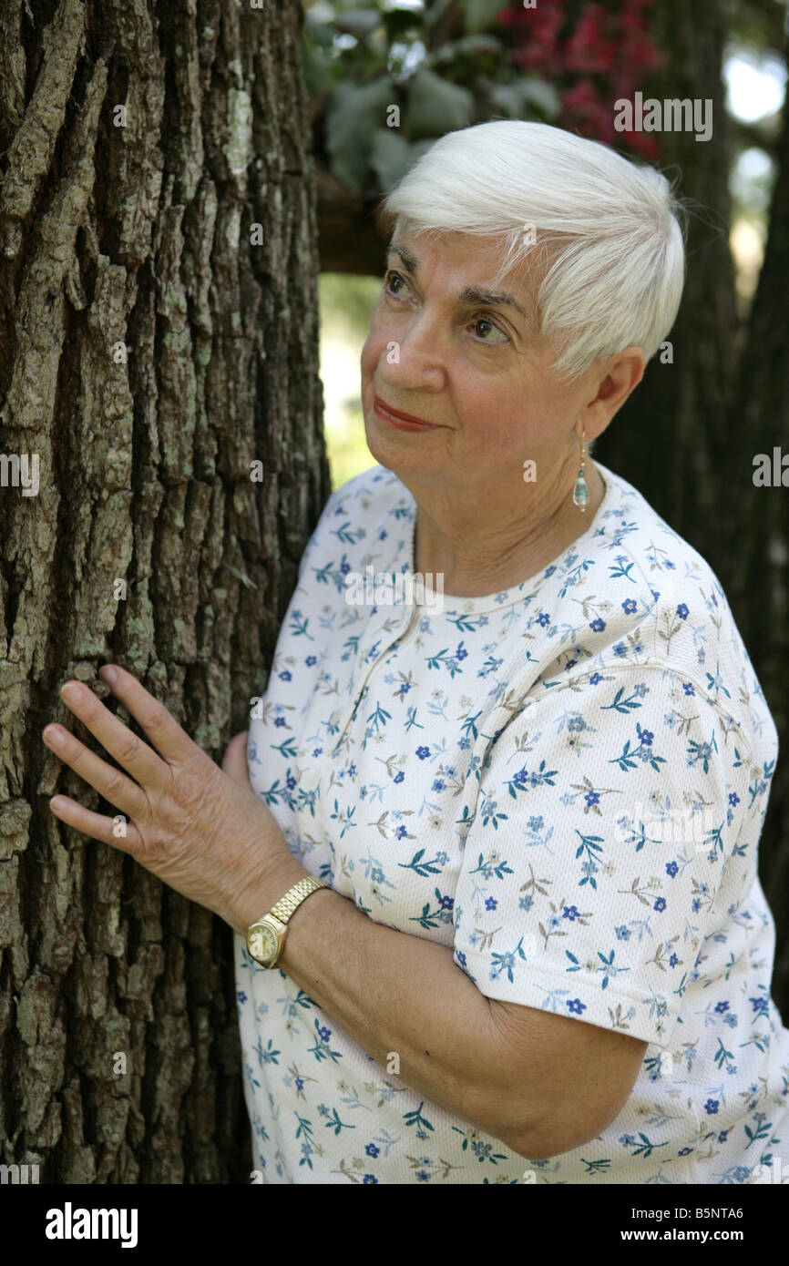 A sweet senior grandmother leaning against a tree Stock Photo - Alamy