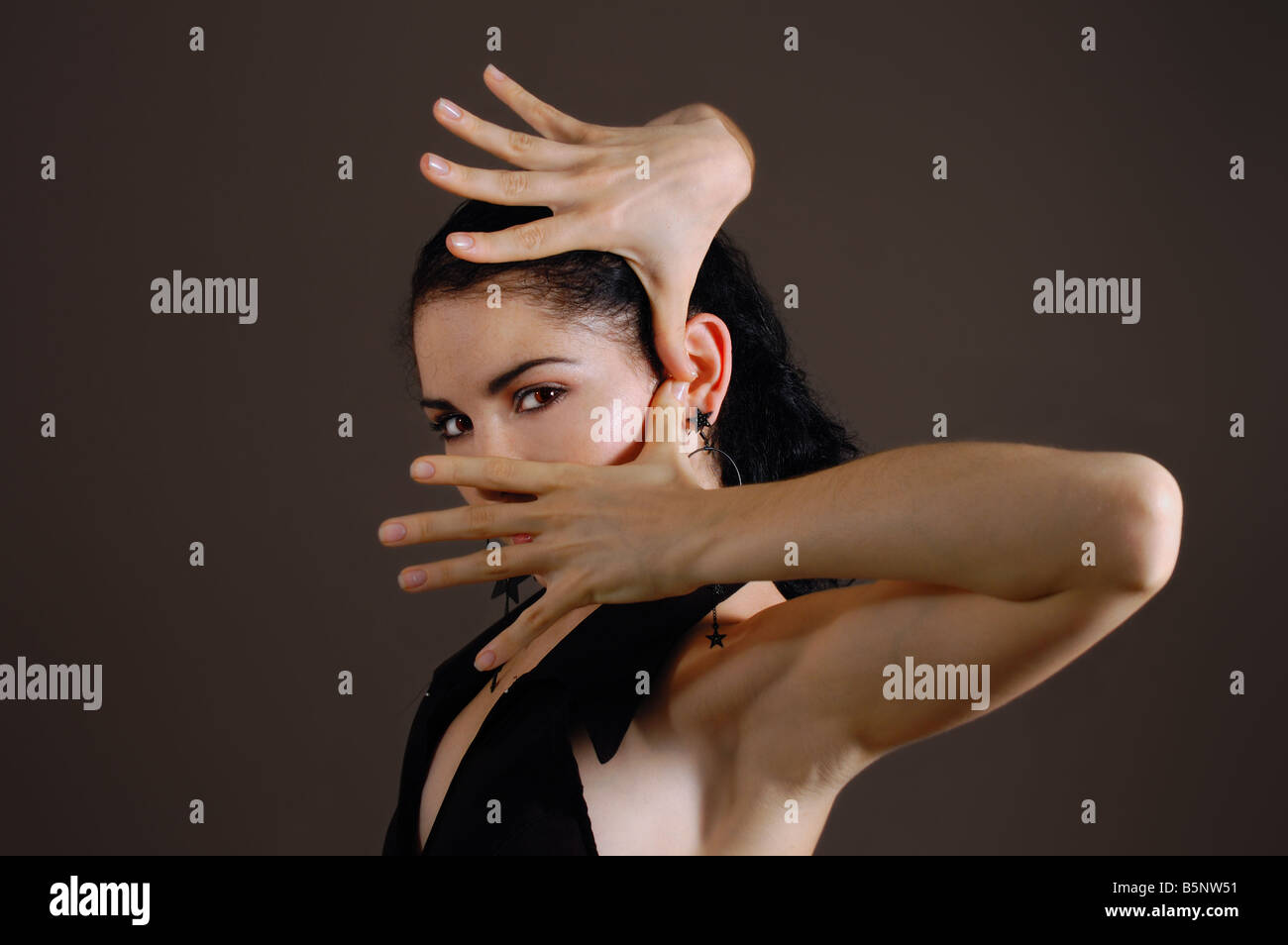 Artistic portrait of young female flamenco dancer framing face with her ...