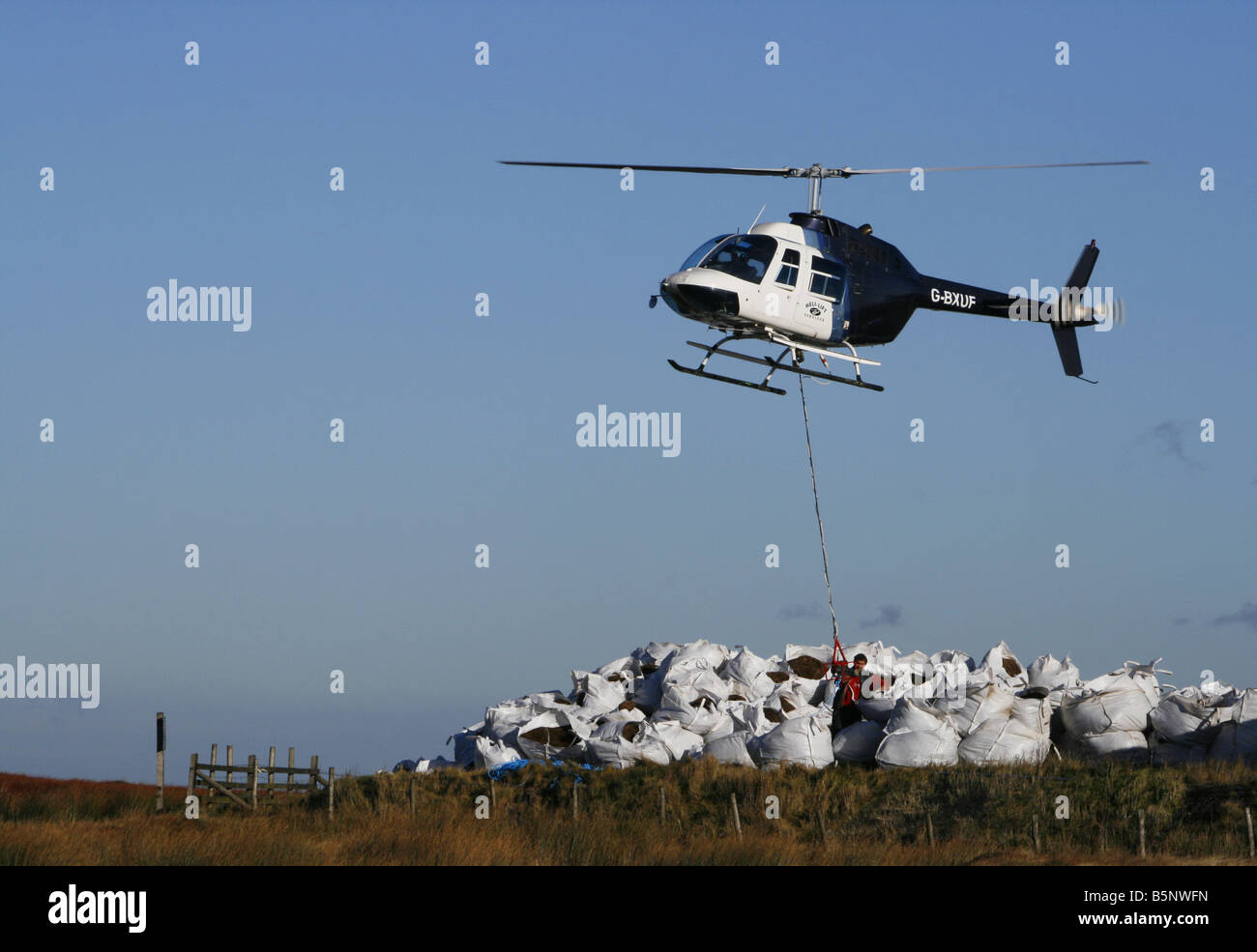 Helicopter lifting bags of seed laden compost for the workers ...