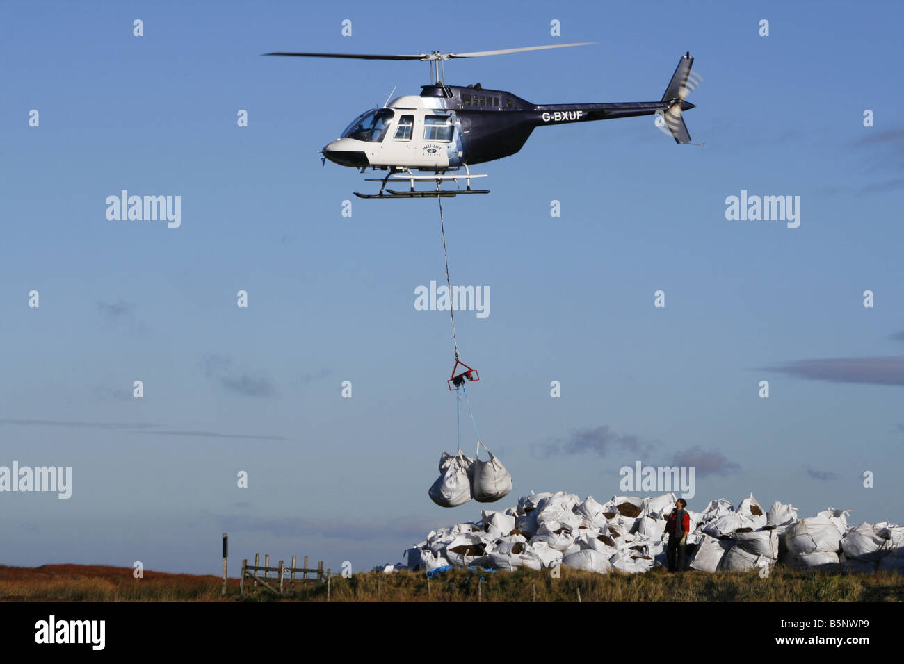 Helicopter lifting bags of seed laden compost for the workers ...