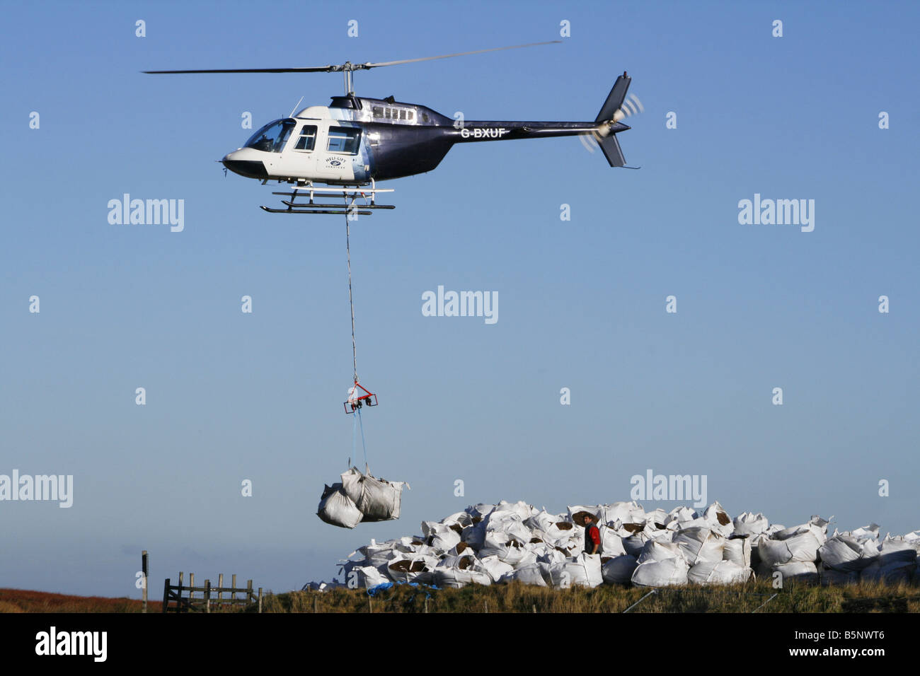 Helicopter lifting bags of seed laden compost for the workers ...