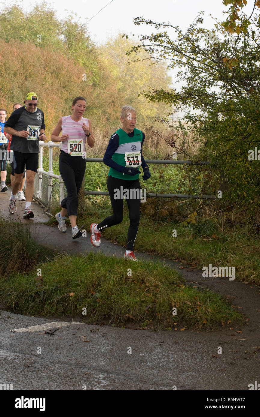 Group of runners crossing a bridge over a stream during a 10km road ...