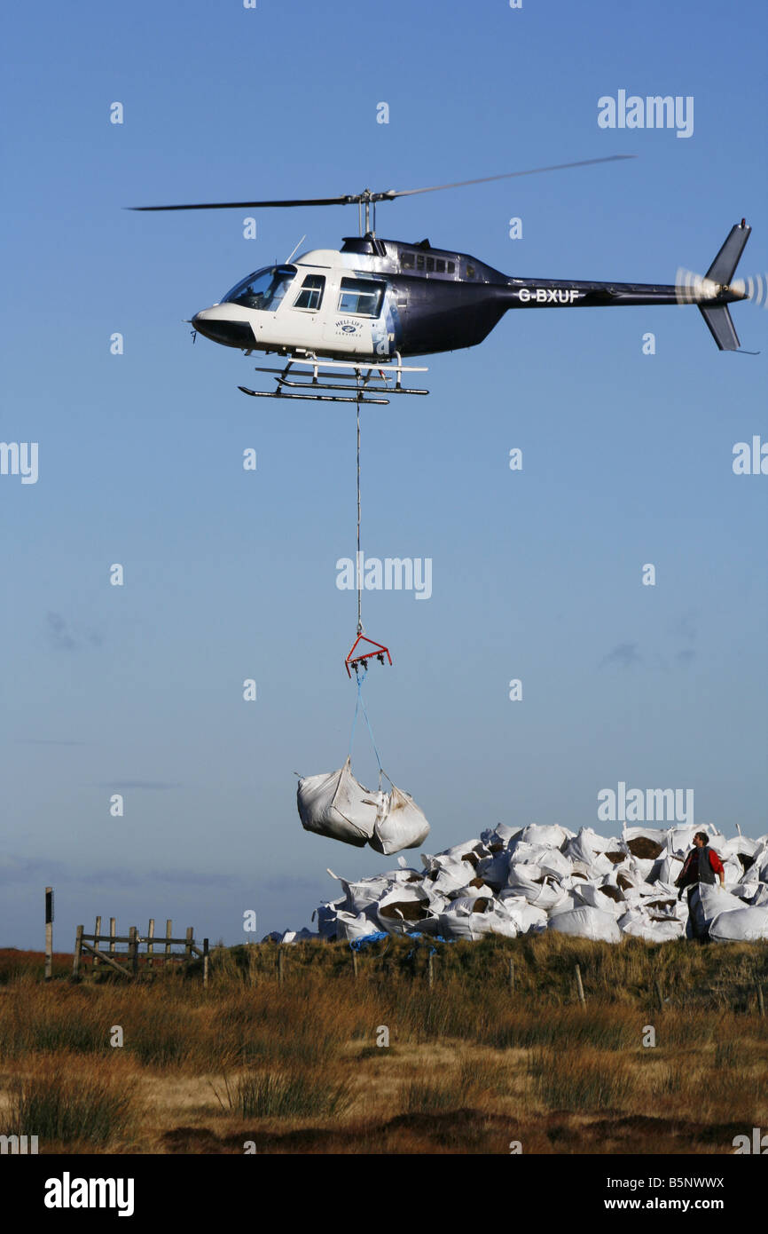 Helicopter lifting bags of seed laden compost for the workers ...