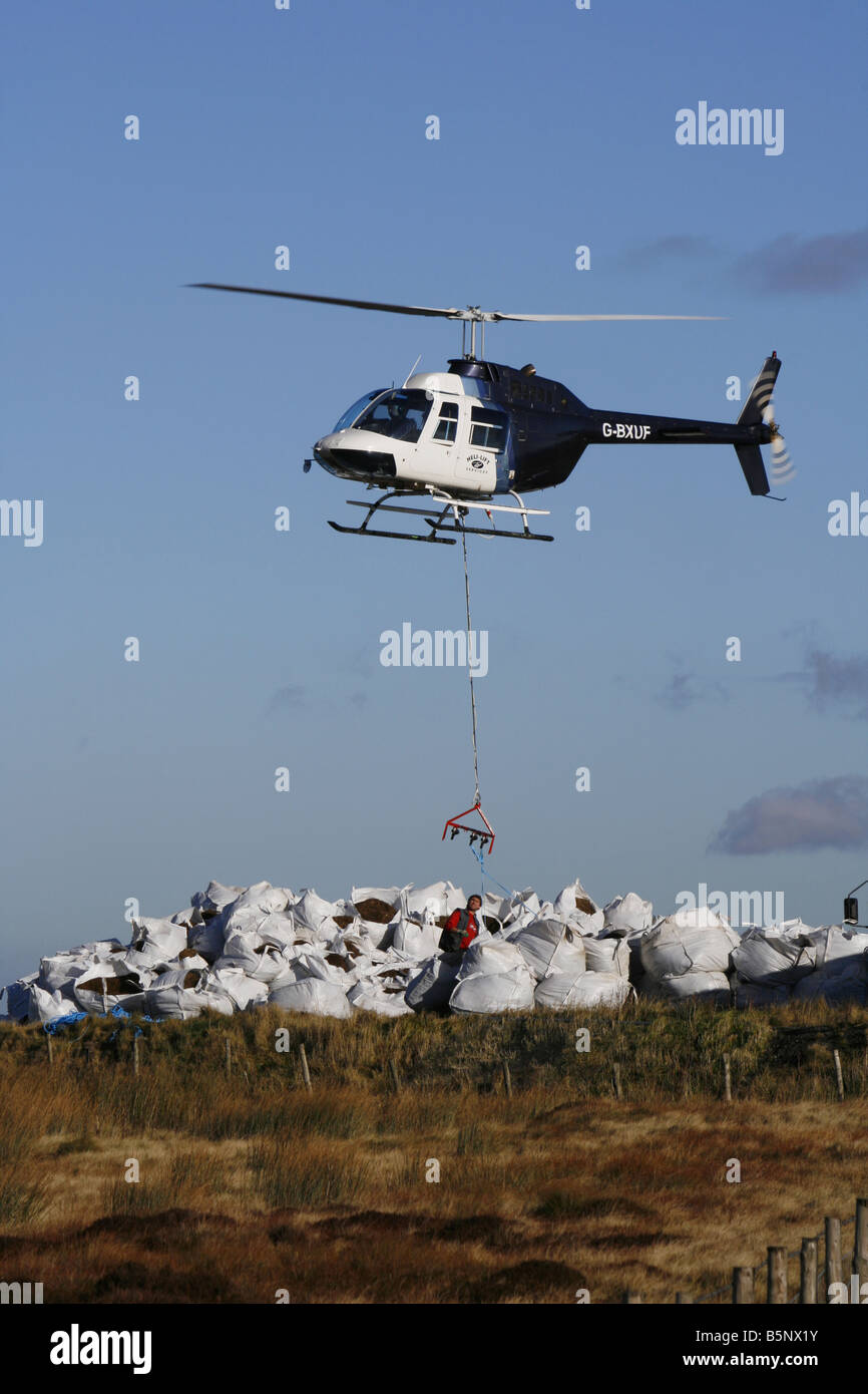 Helicopter lifting bags of seed laden compost for the workers ...