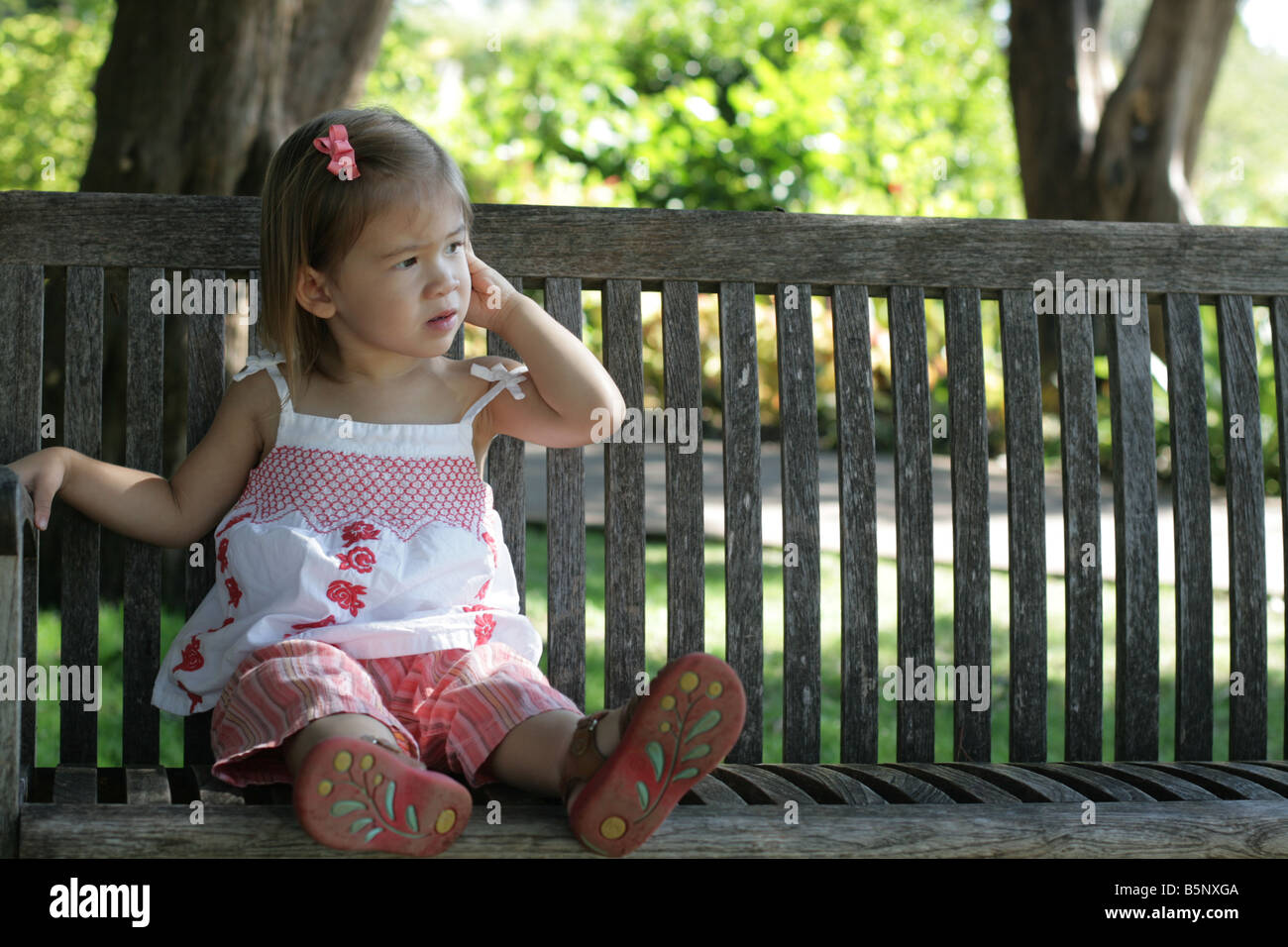 Toddler sits on park bench Stock Photo - Alamy
