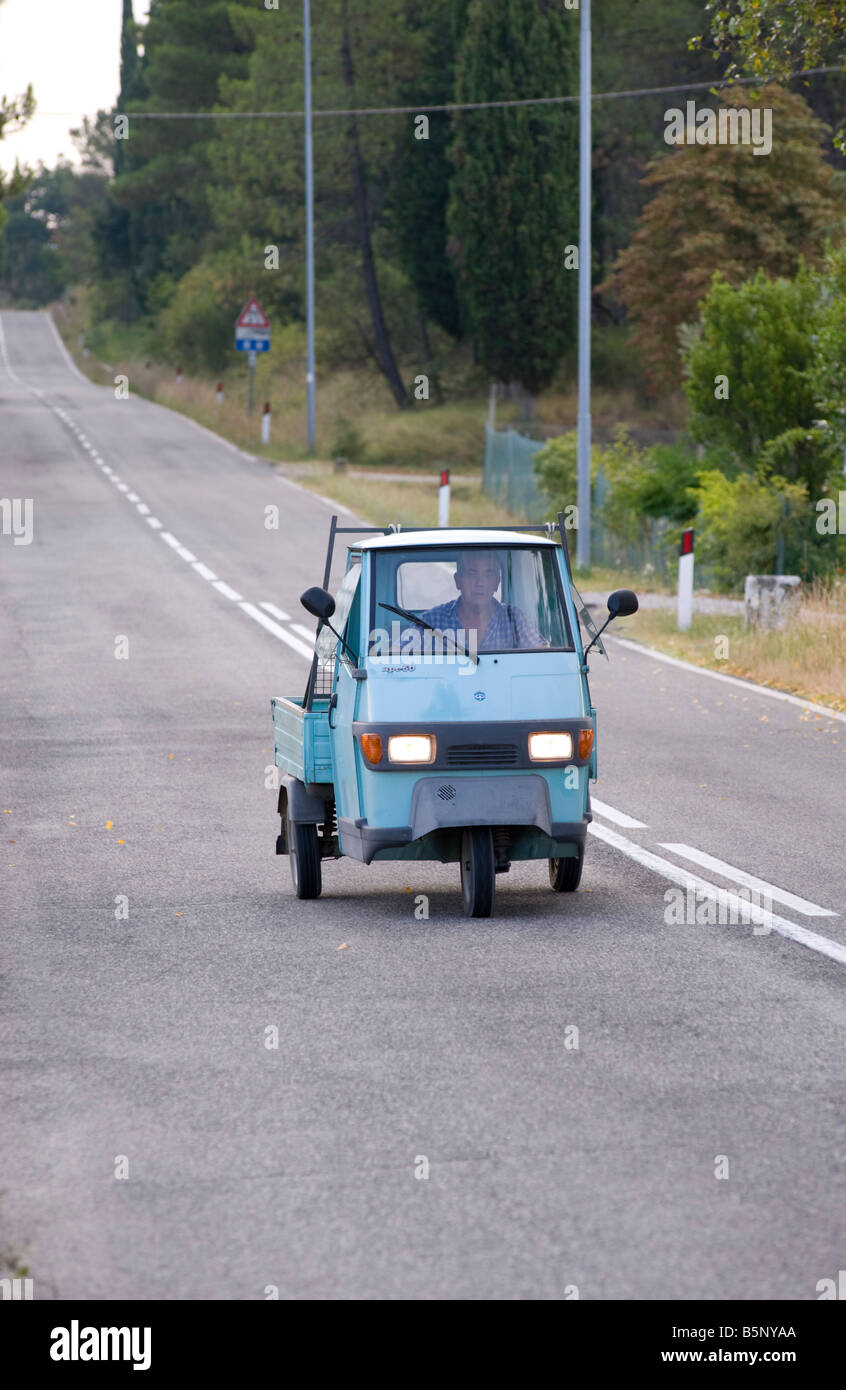 A blue Italian Ape three wheeled utility vehicle approaches along a ...