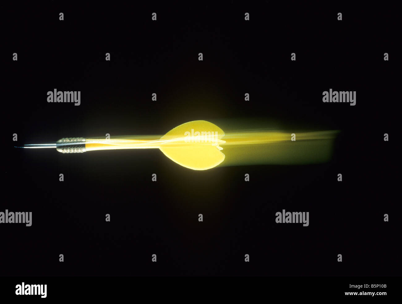 Yellow dart blurs as it flies through the air against black background ...