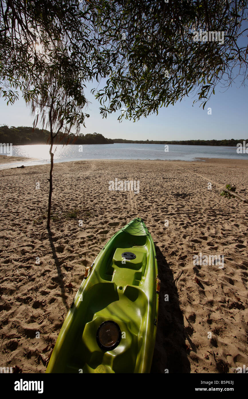 A BRIGHT GREEN CANOE ON SAND AT THE EDGE OF A LAKE VERTICAL BDA11155 ...