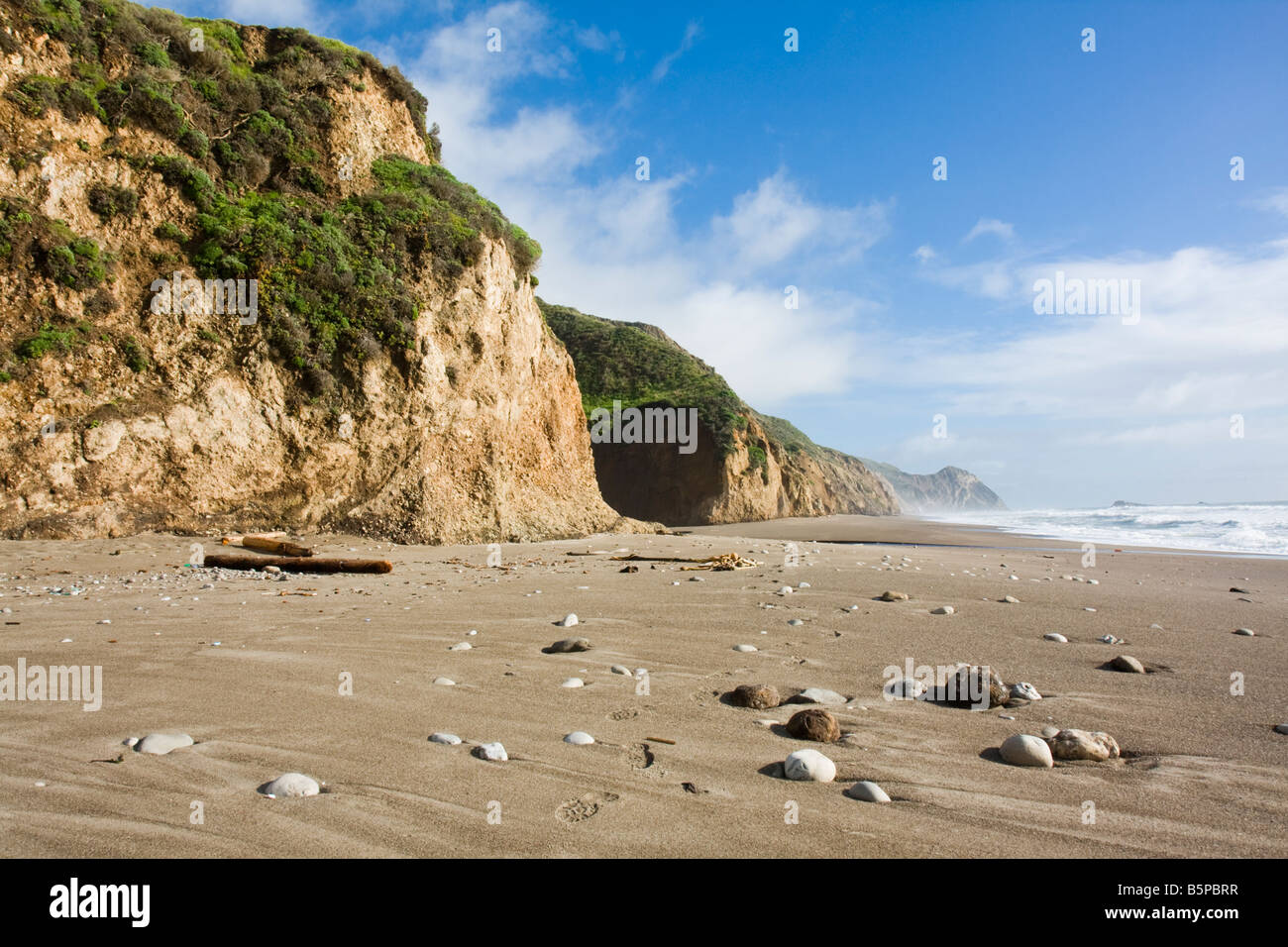Round pebbles lie in the sand on Wildcat Beach below steep cliffs ...