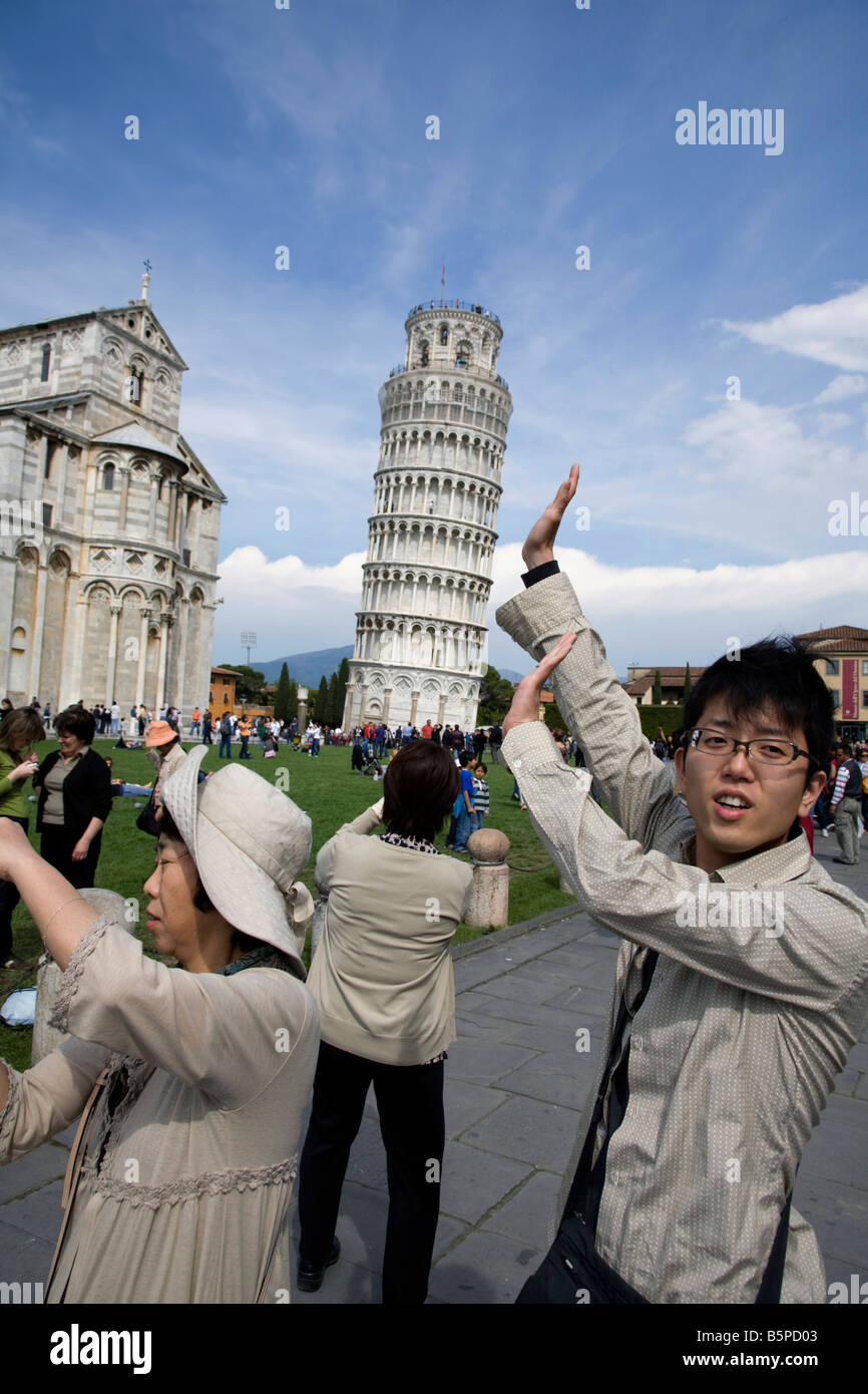 Tourists pose in front of the Leaning Tower of Pisa in the Piazza dei ...
