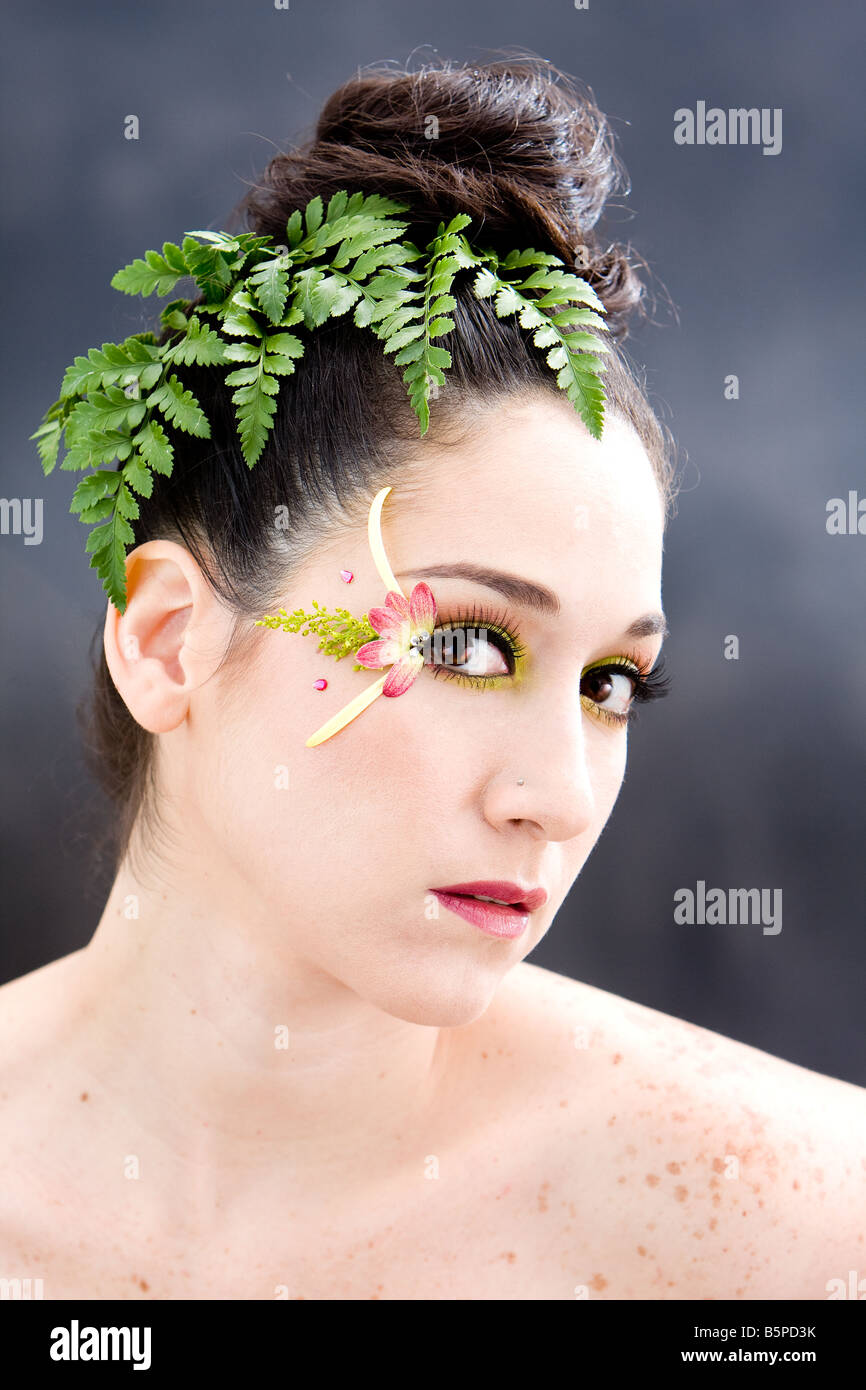 Beautiful brunette face with pink green yellow eye flower petal makeup ...