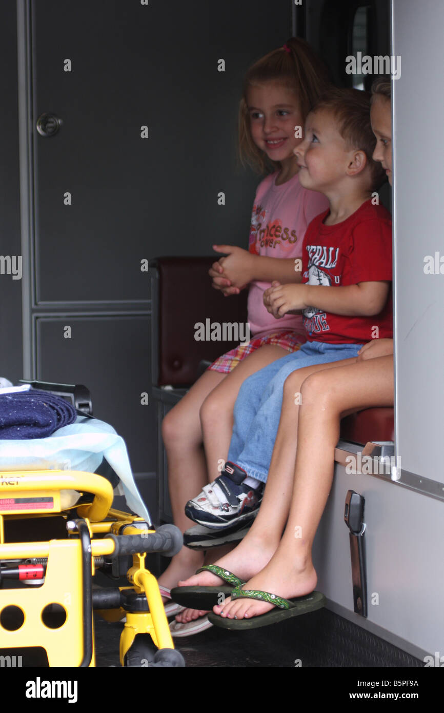 Three kids in the back of an ambulance talking to a emt at a safety ...