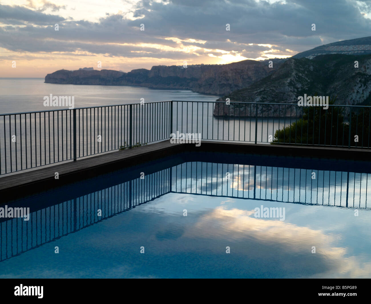 View at dusk across swimming pool to sea Stock Photo - Alamy