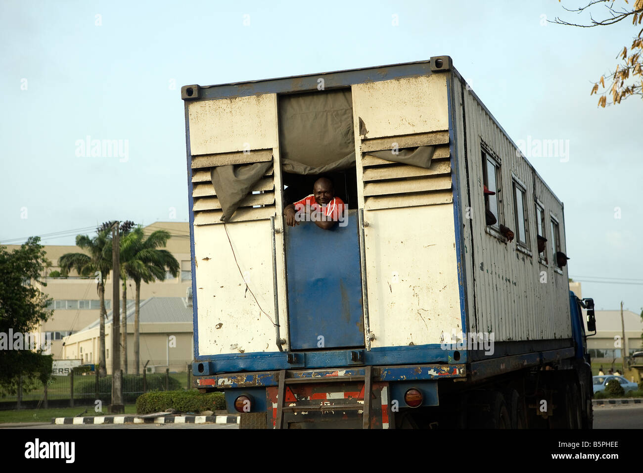 A Nigerian man looks out of the back of a lorry filled with other men ...