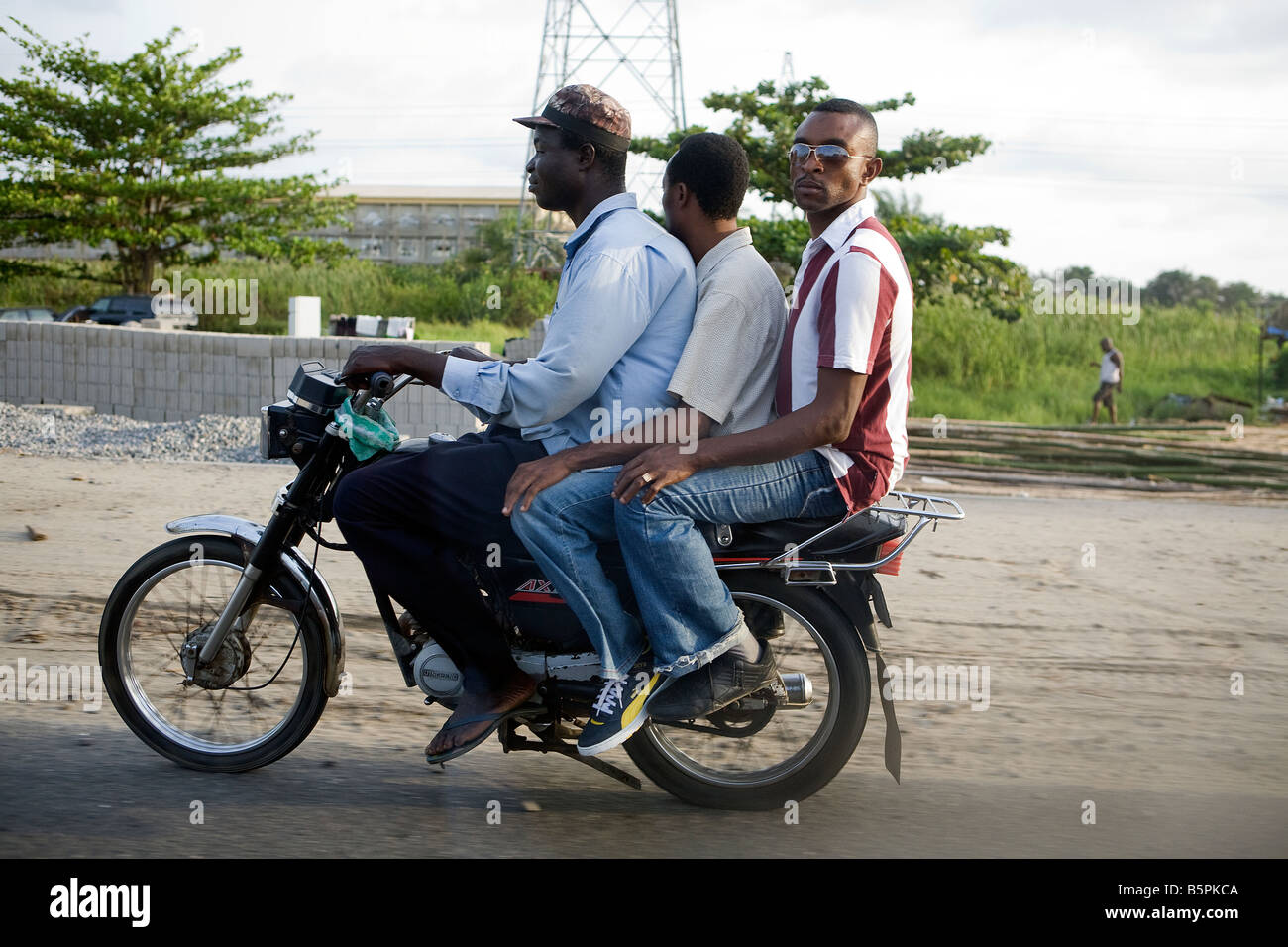 Three men share a motorbike along the road leading out of Lagos ...