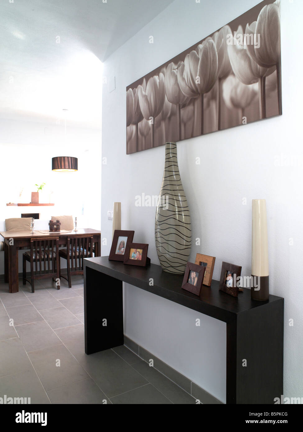Narrow sidetable in corridor on which stand framed photos and vases ...
