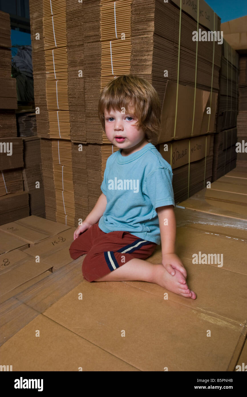 Young boy on a pile of cardboard boxes in a factory MODEL RELEASED ...