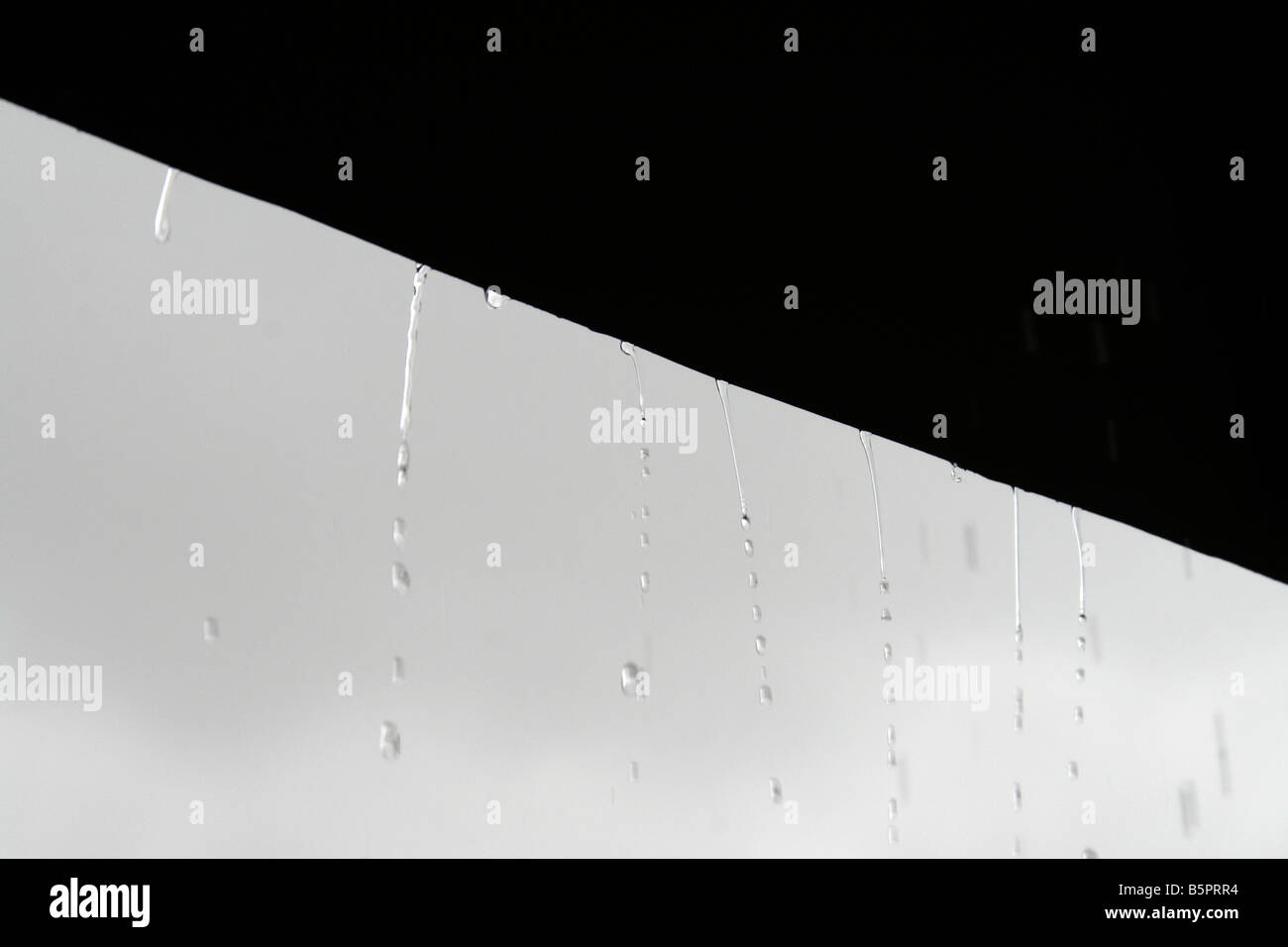 lots rain drops falling off property roof Stock Photo - Alamy