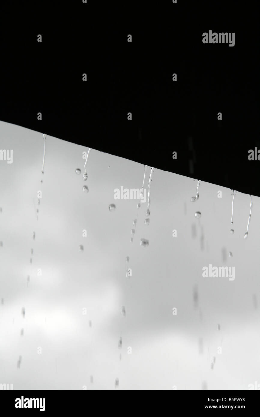 lots rain drops falling off property roof Stock Photo - Alamy