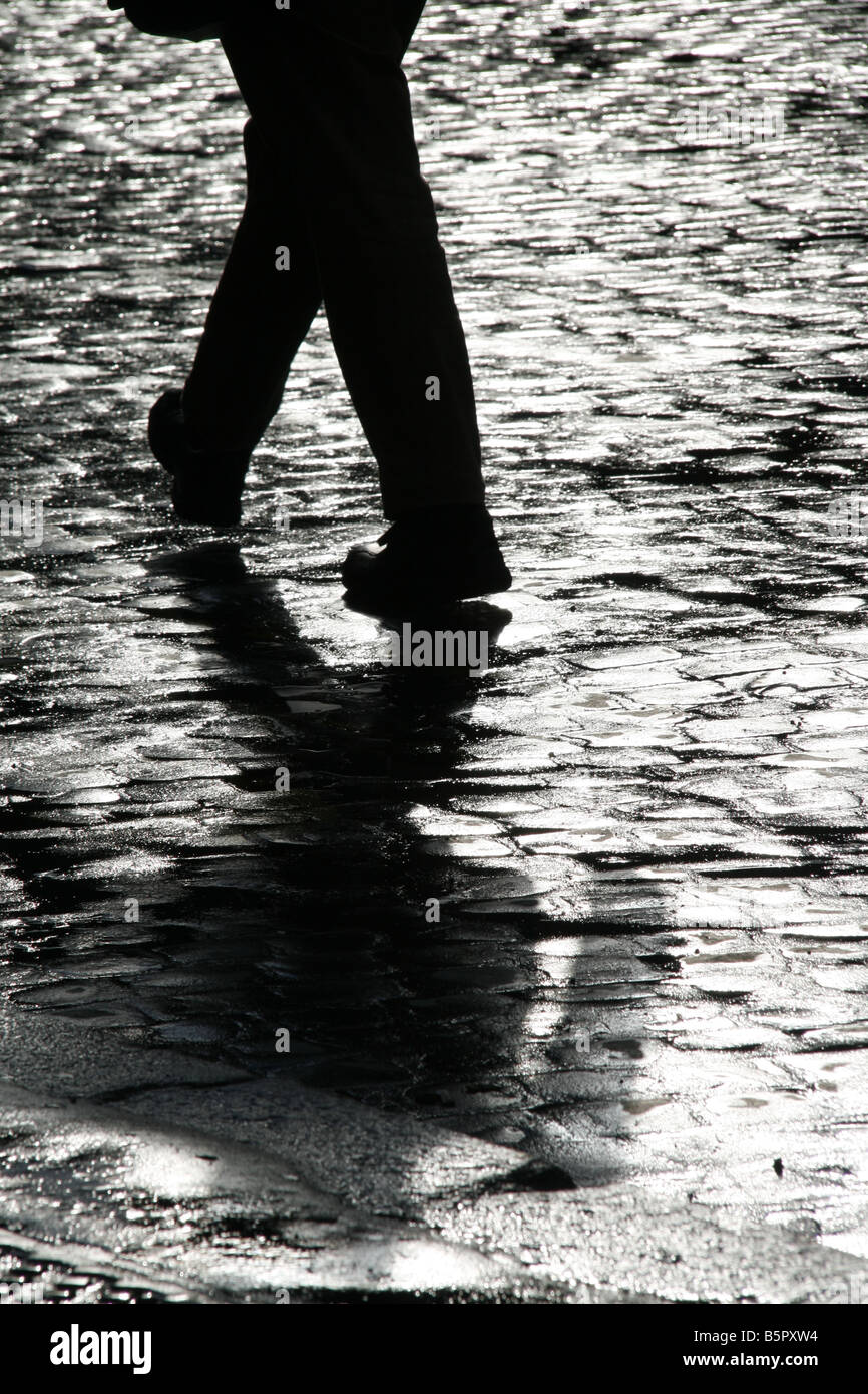 one person walking on wet cobbled street in rain in city town Stock ...