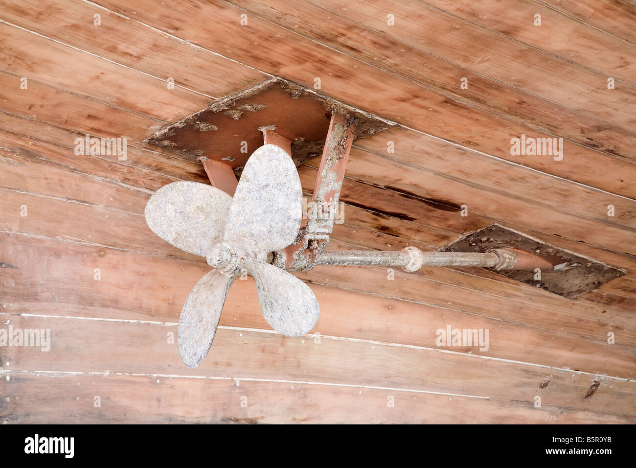 A corroded propeller blades and shaft at the bow of a wooden boat in a ...