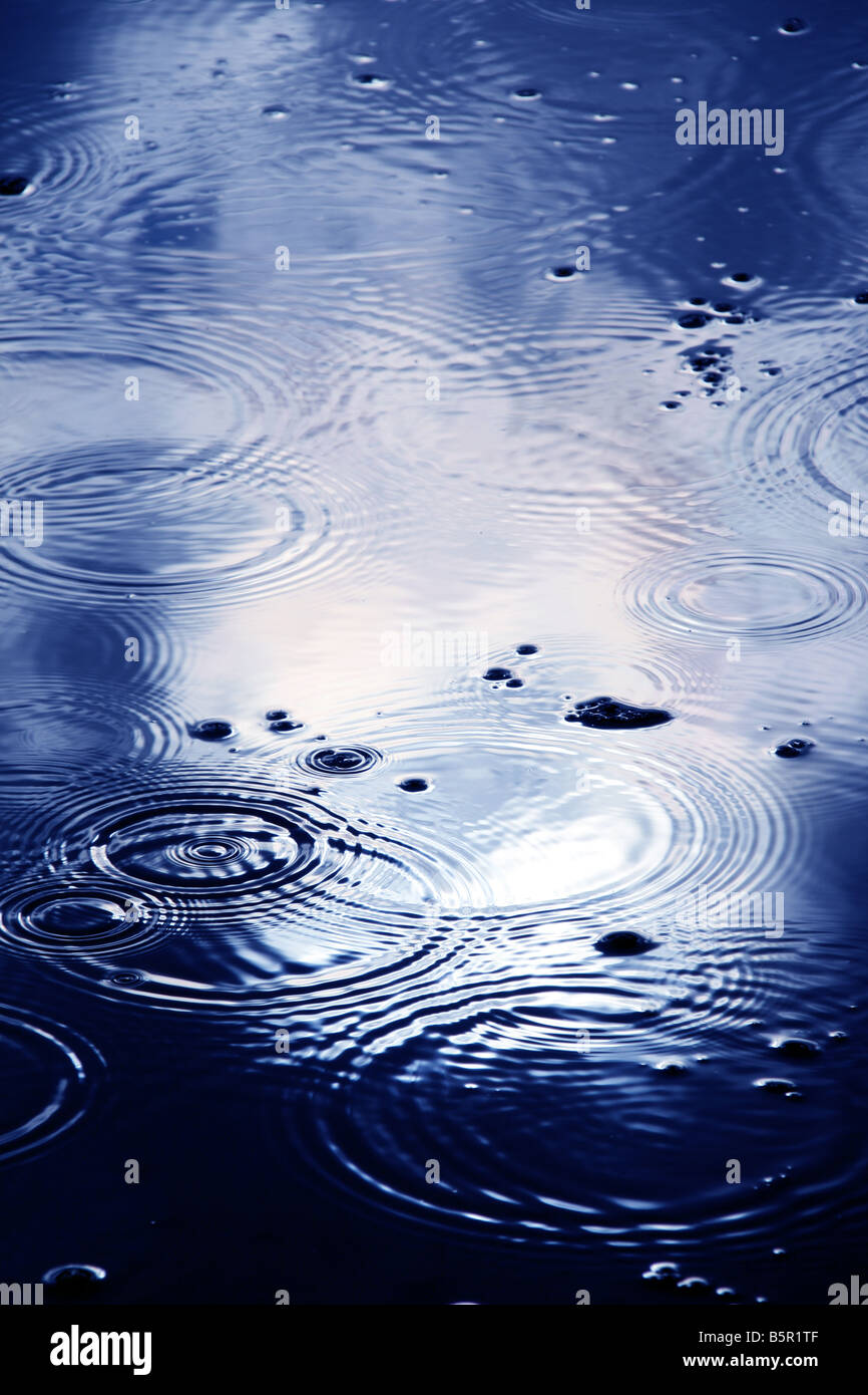 rain drops falling in cold blue water puddle in street at night Stock ...