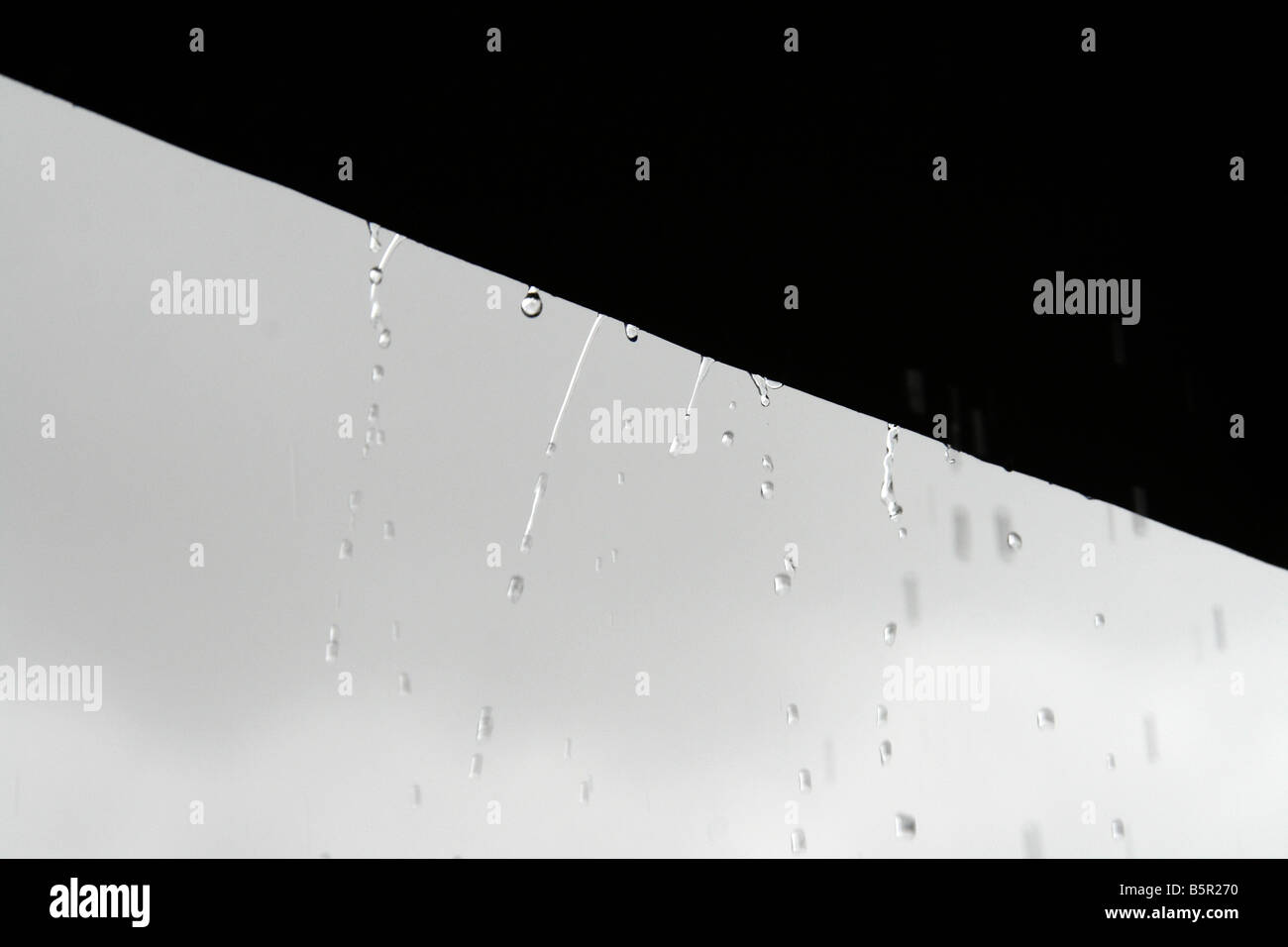 lots rain drops falling off property roof Stock Photo - Alamy