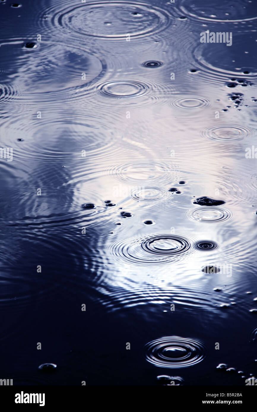 rain drops falling in cold blue water puddle in street at night Stock ...